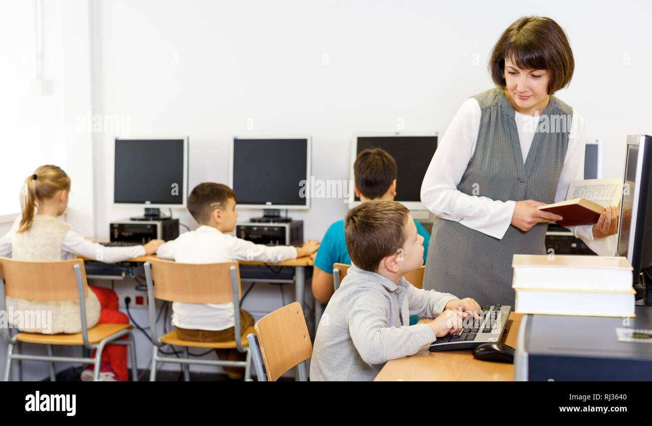 Portrait of young female teacher working at lesson in computer class ...
