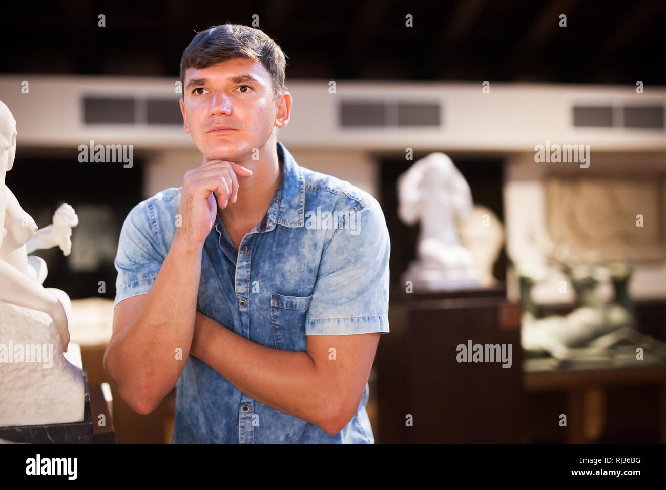 Man standing at hall of historical museum among exhibits of antiquity ...