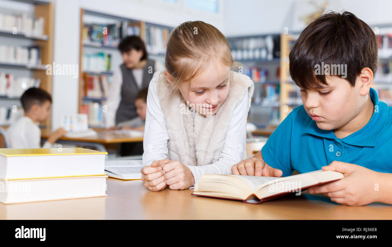 Portrait of two school children preparing for lesson in school library ...