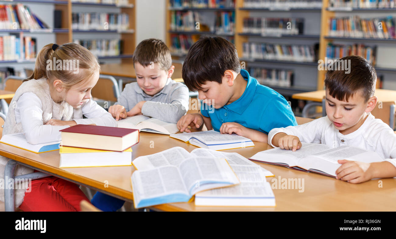 Group of intelligent children studying together in school library ...