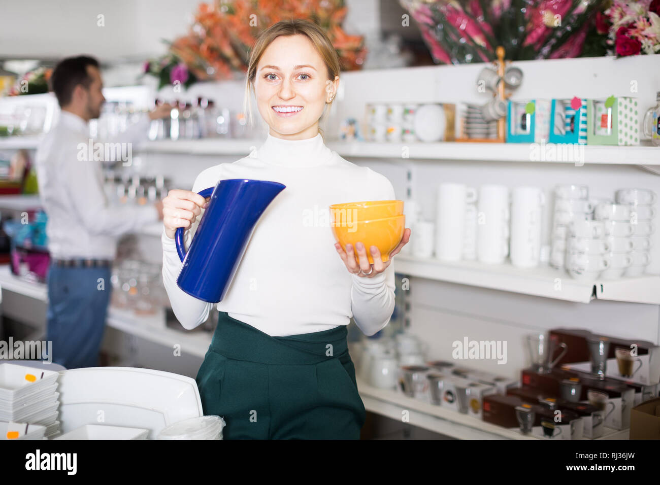 Smiling female customer shows a jug and plates in a ceramic shop Stock ...