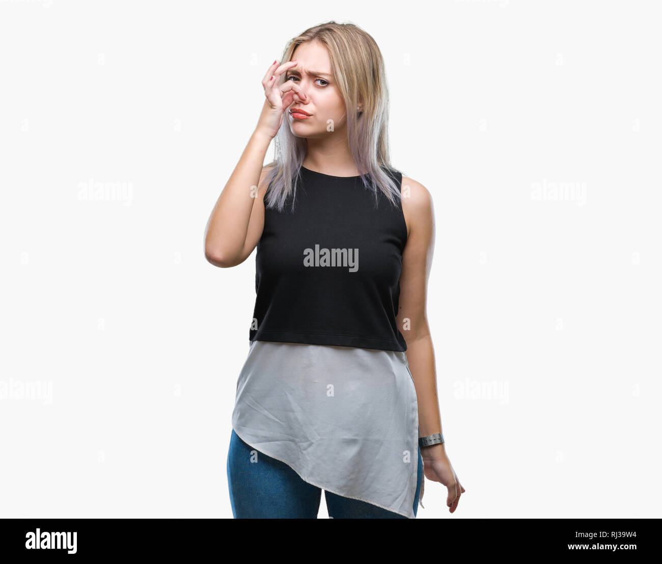 Young blonde woman over isolated background smelling something stinky ...