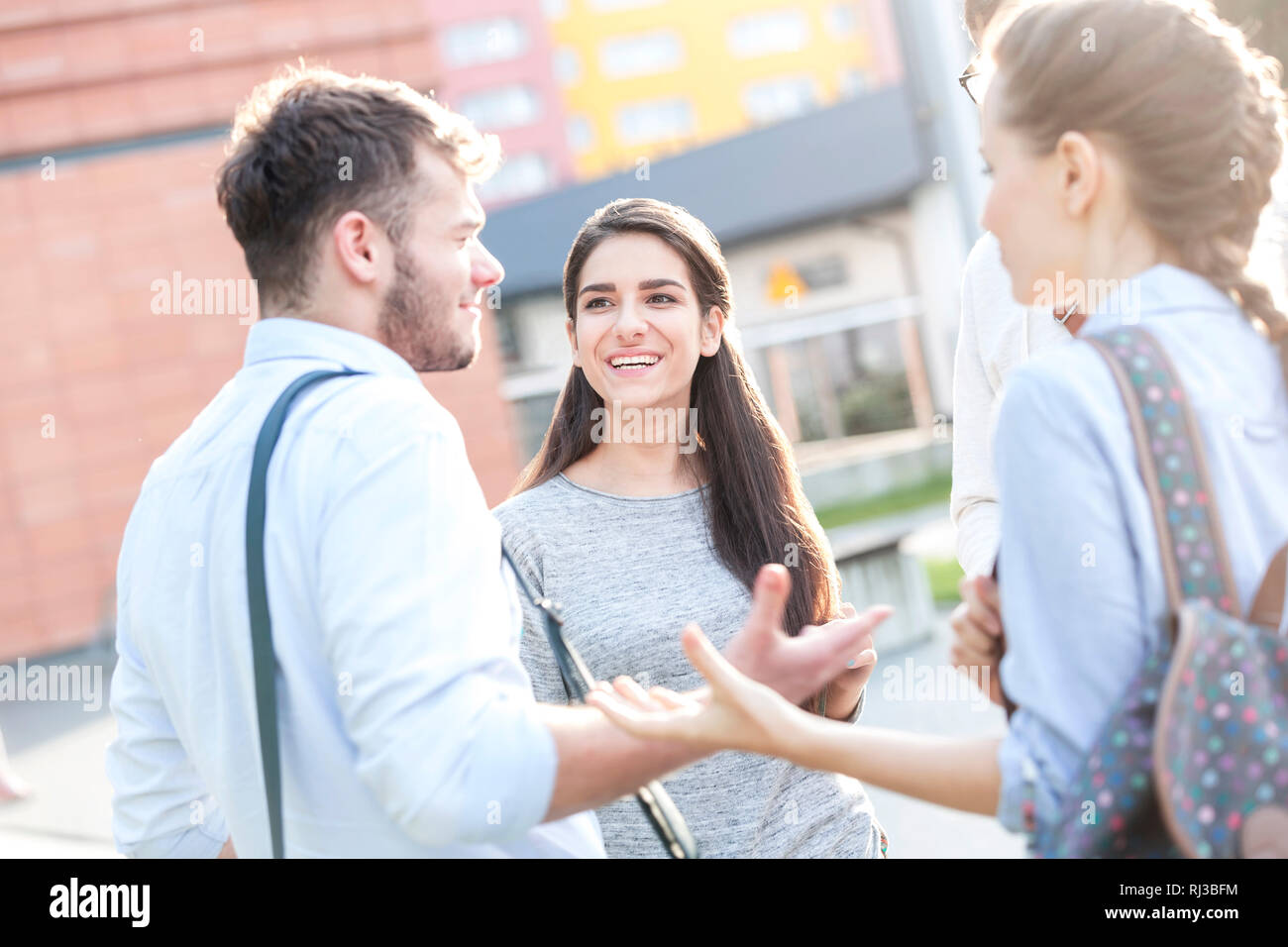 Smiling friends talking while standing at university Stock Photo - Alamy