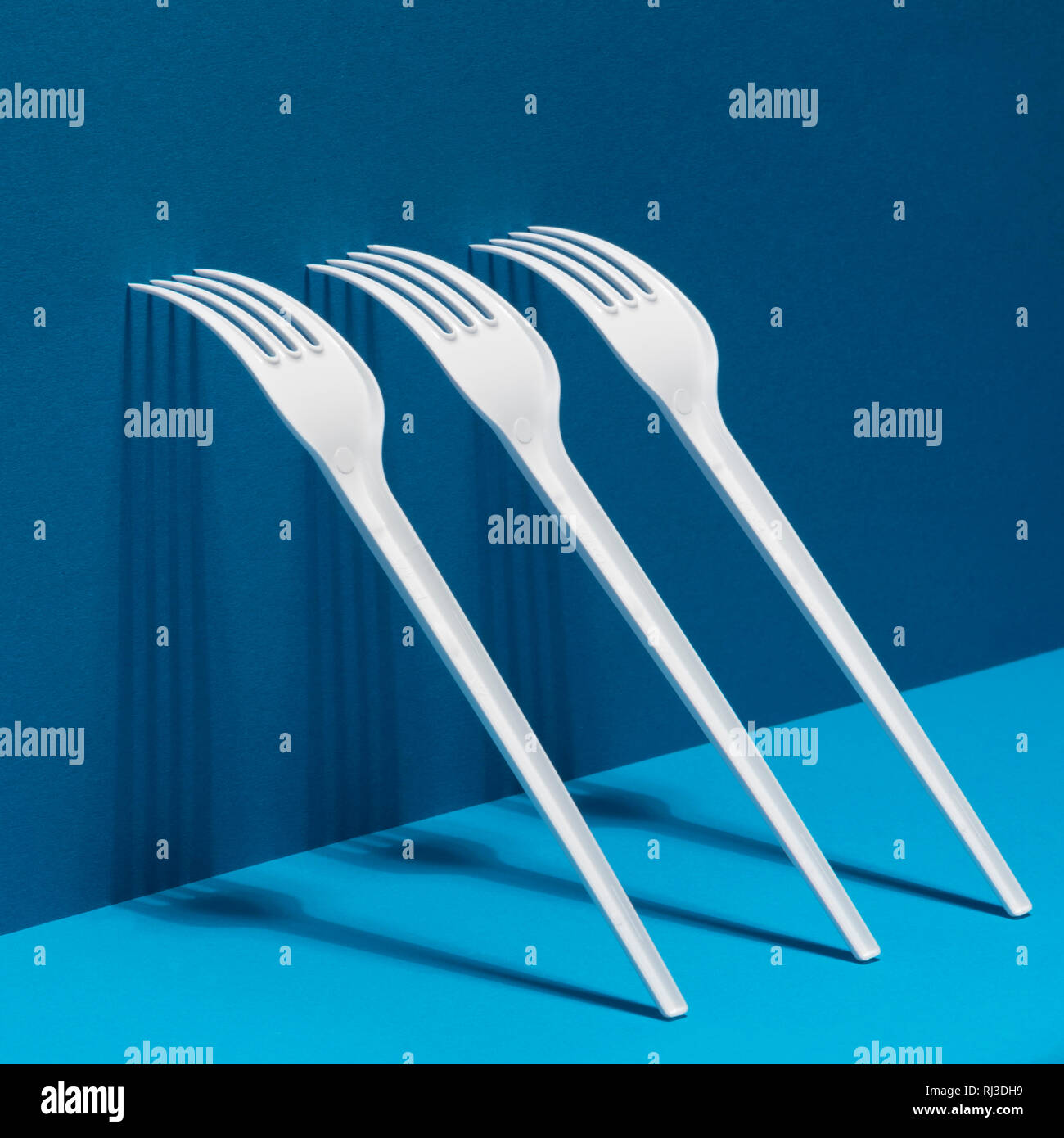White forks with shadows on a mixed blue background. Modern conceptual ...