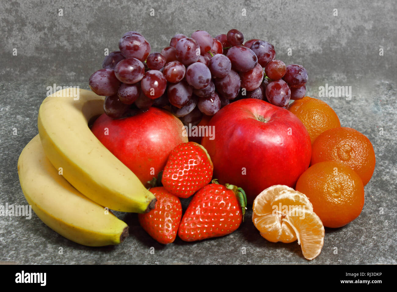 Fresh fruits in grey stone background Stock Photo - Alamy