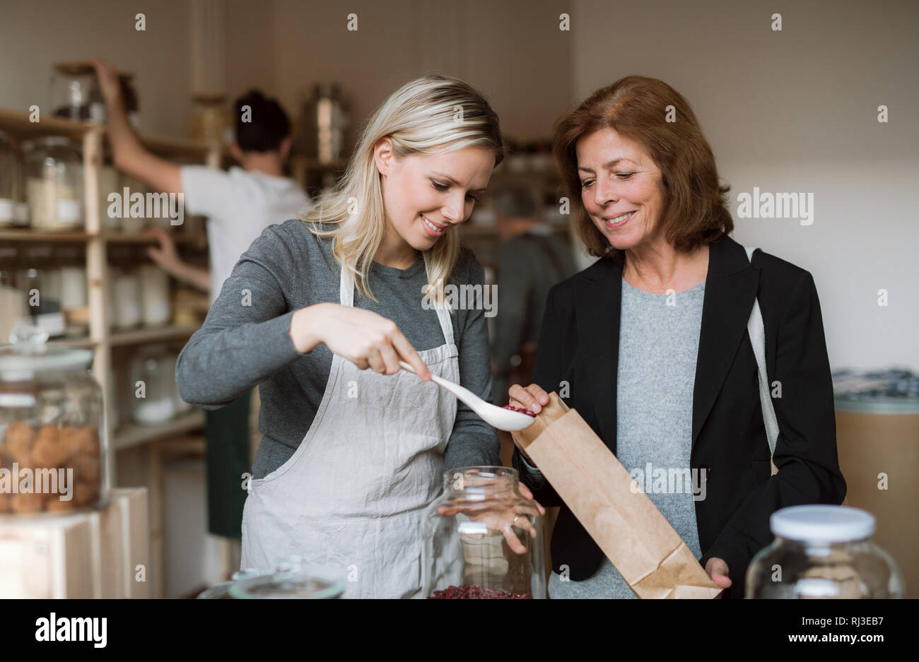 A female shop assistant serving a senior customer in a zero-waste shop ...