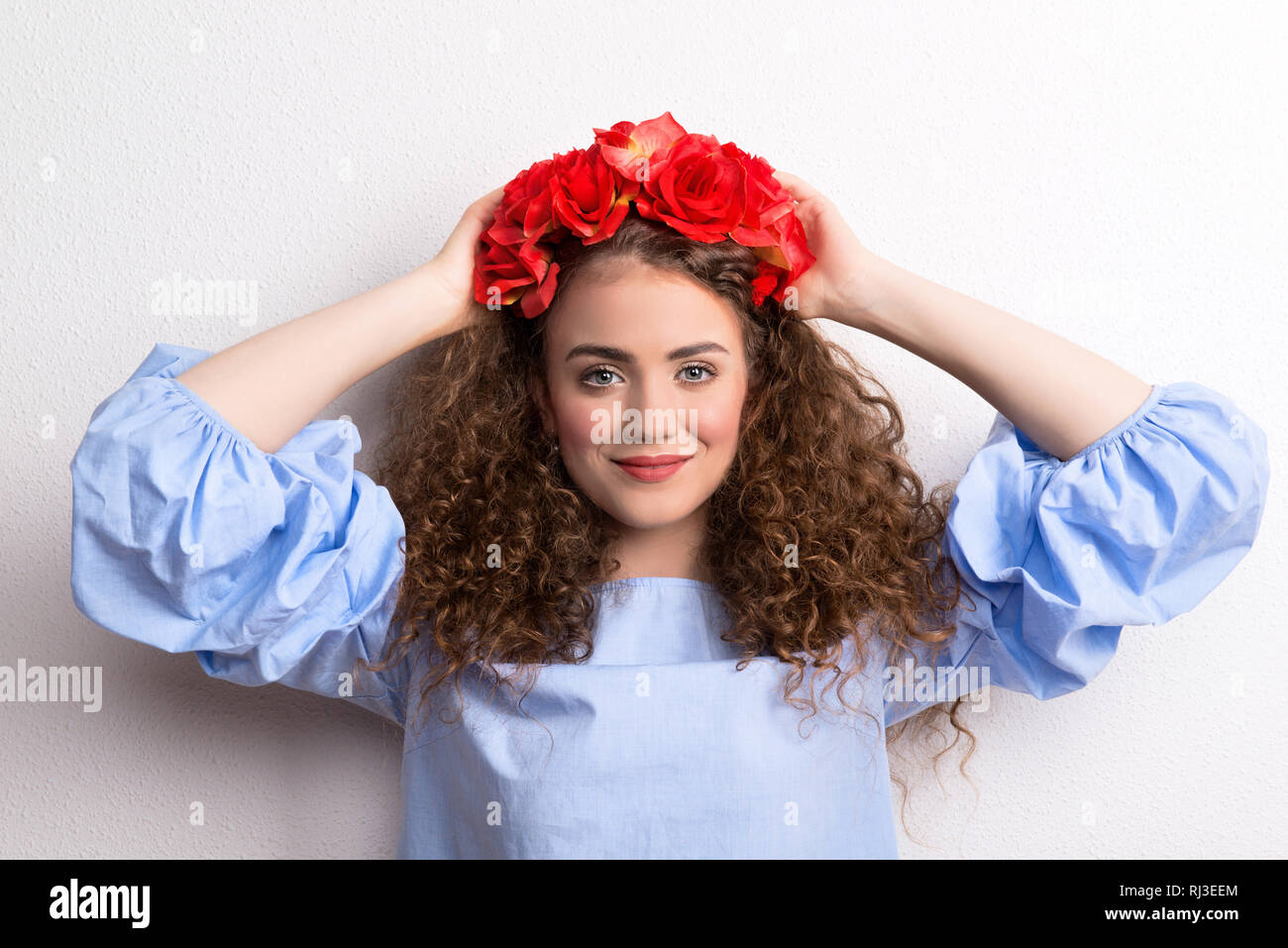 A front view of young beautiful woman with flower headband, hands ...