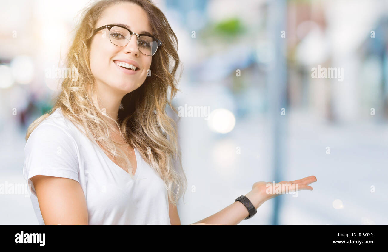 Beautiful young blonde woman wearing glasses over isolated background ...