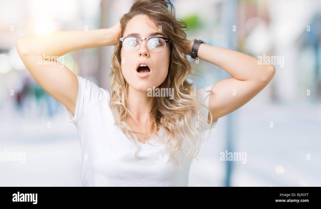 Beautiful young blonde woman wearing glasses over isolated background ...