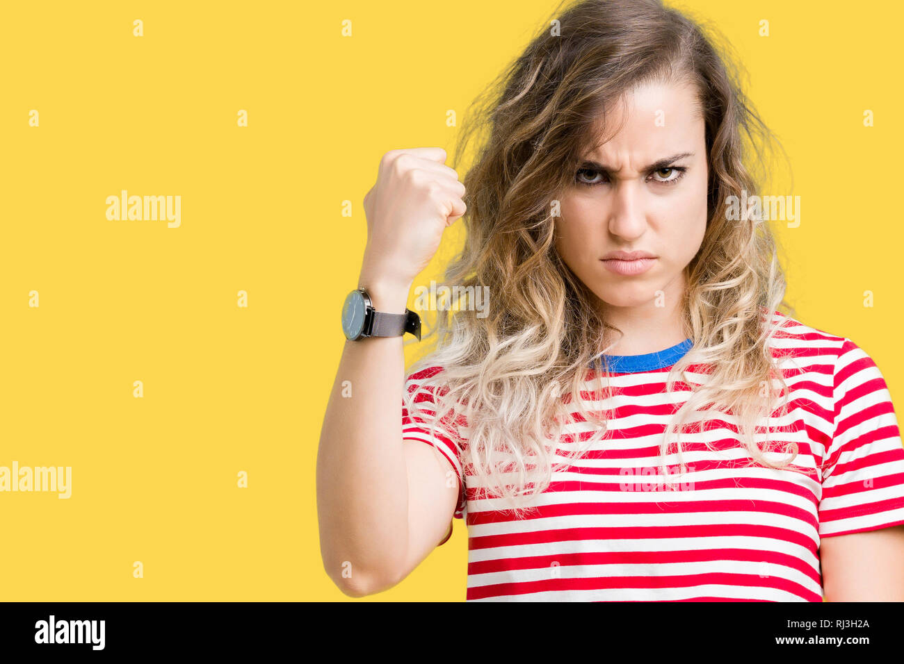 Beautiful young blonde woman over isolated background angry and mad ...