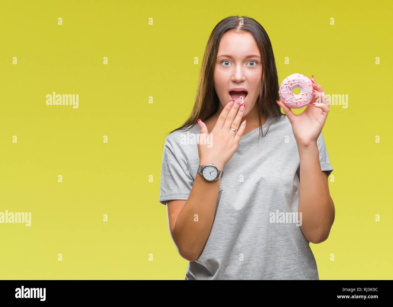 Young caucasian woman eating sweet donut over isolated background cover ...