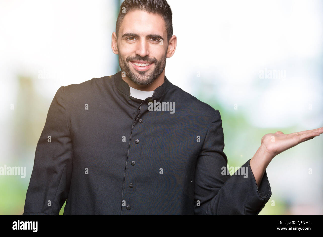 Young Christian priest over isolated background smiling cheerful ...