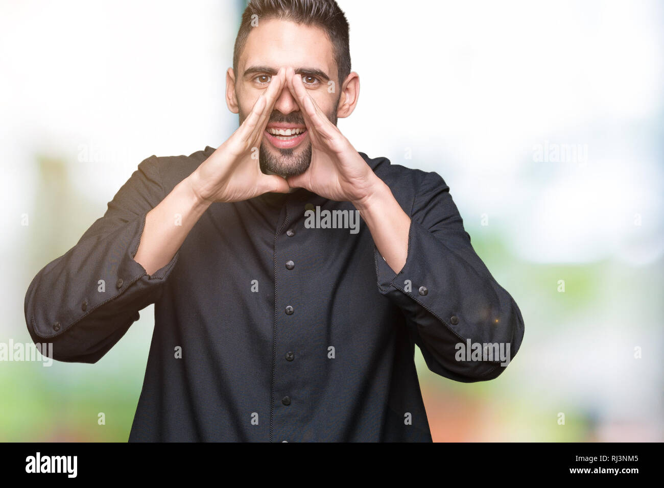 Young Christian priest over isolated background Shouting angry out loud ...