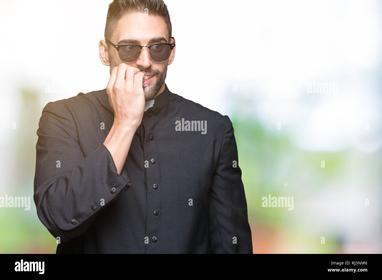 Young Christian priest wearing sunglasses over isolated background ...
