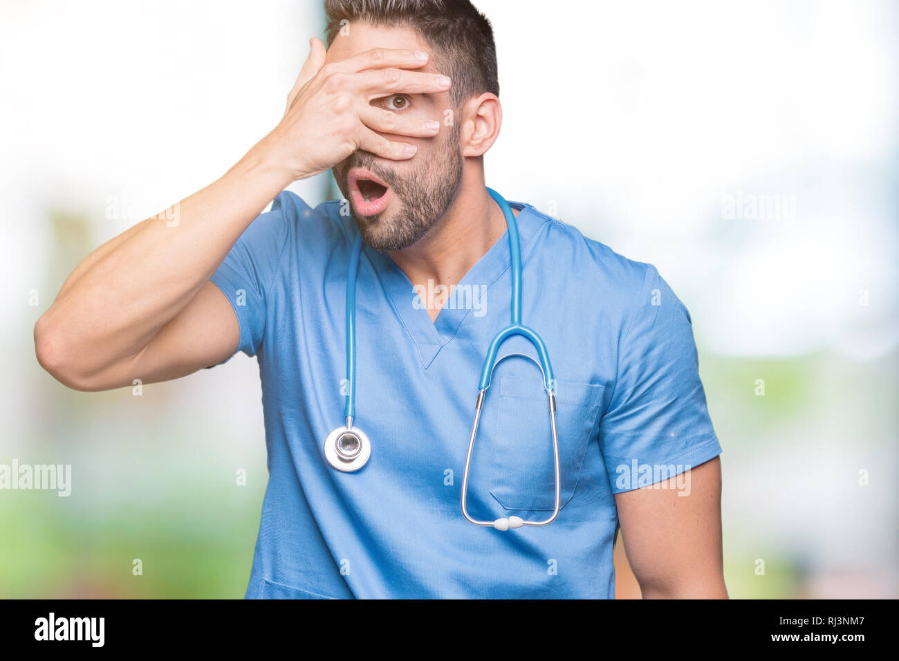 Handsome young doctor surgeon man over isolated background peeking in ...