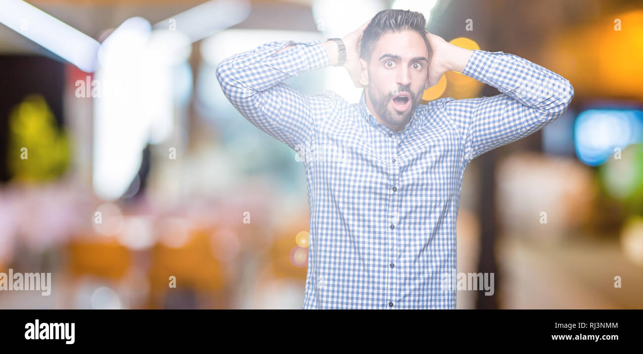 Young handsome man over isolated background Crazy and scared with hands on head, afraid and ...