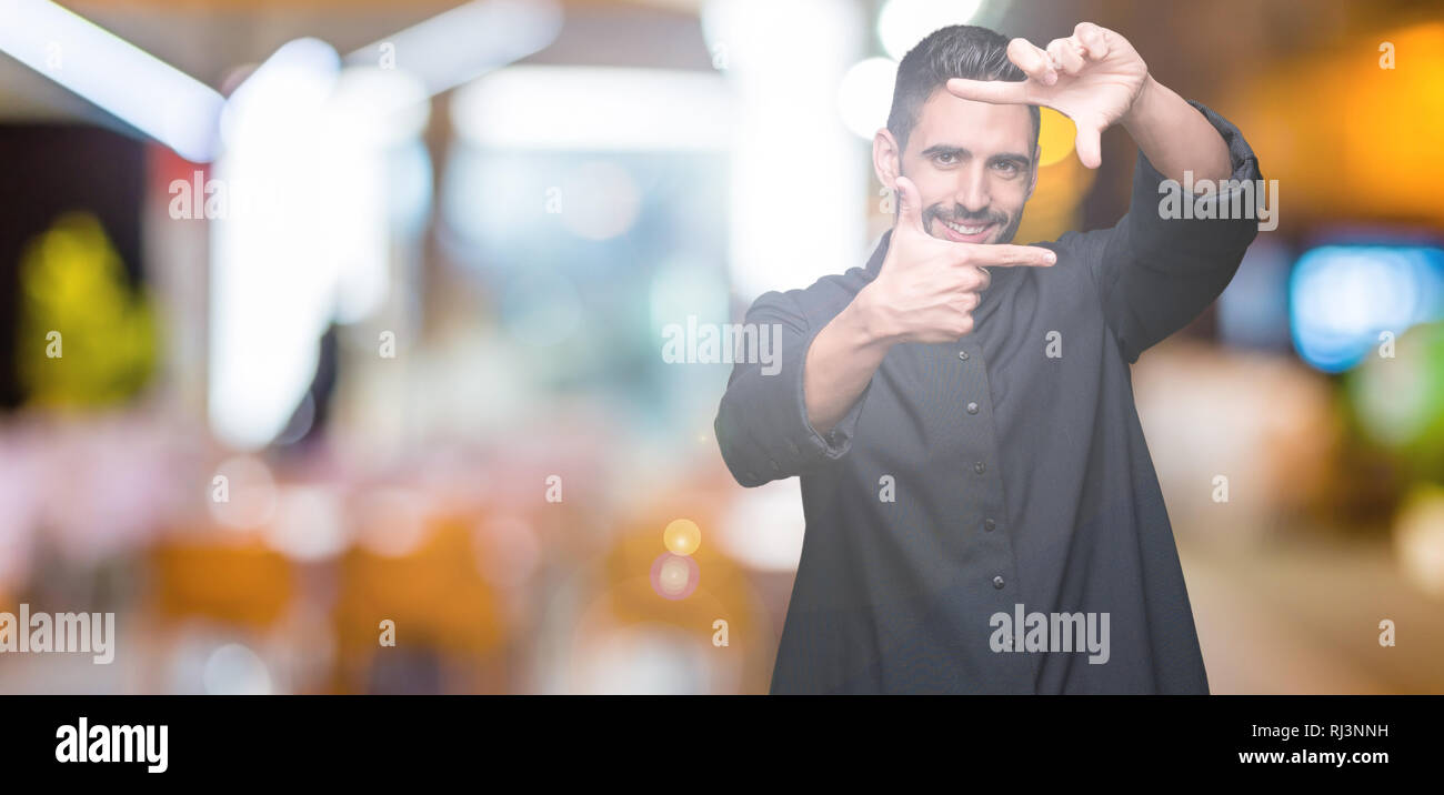 Young Christian priest over isolated background smiling making frame ...