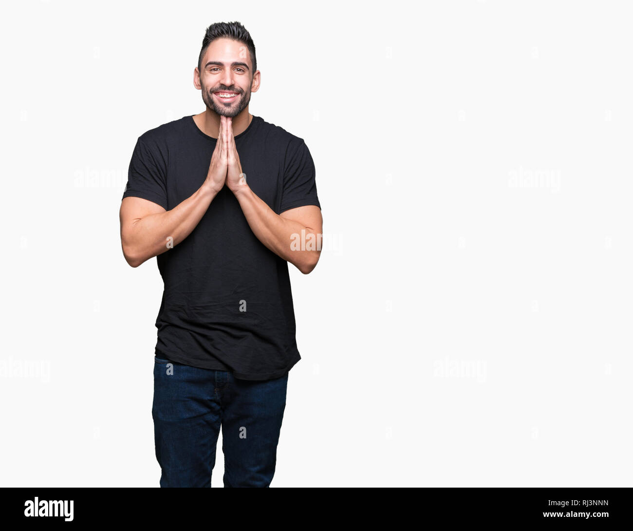 Young handsome man over isolated background praying with hands together ...