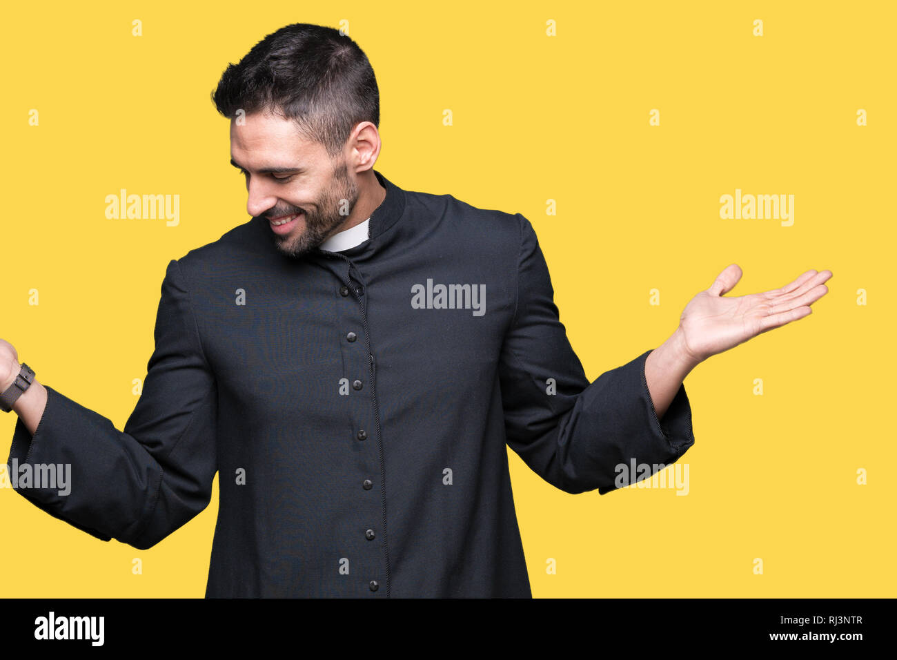 Young Christian priest over isolated background Smiling showing both ...