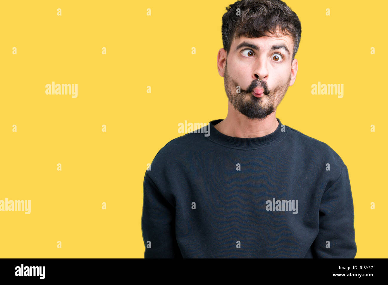 Young handsome man over isolated background making fish face with lips ...