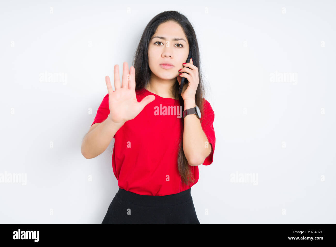 Young brunette woman talking on smartphone over isolated background ...