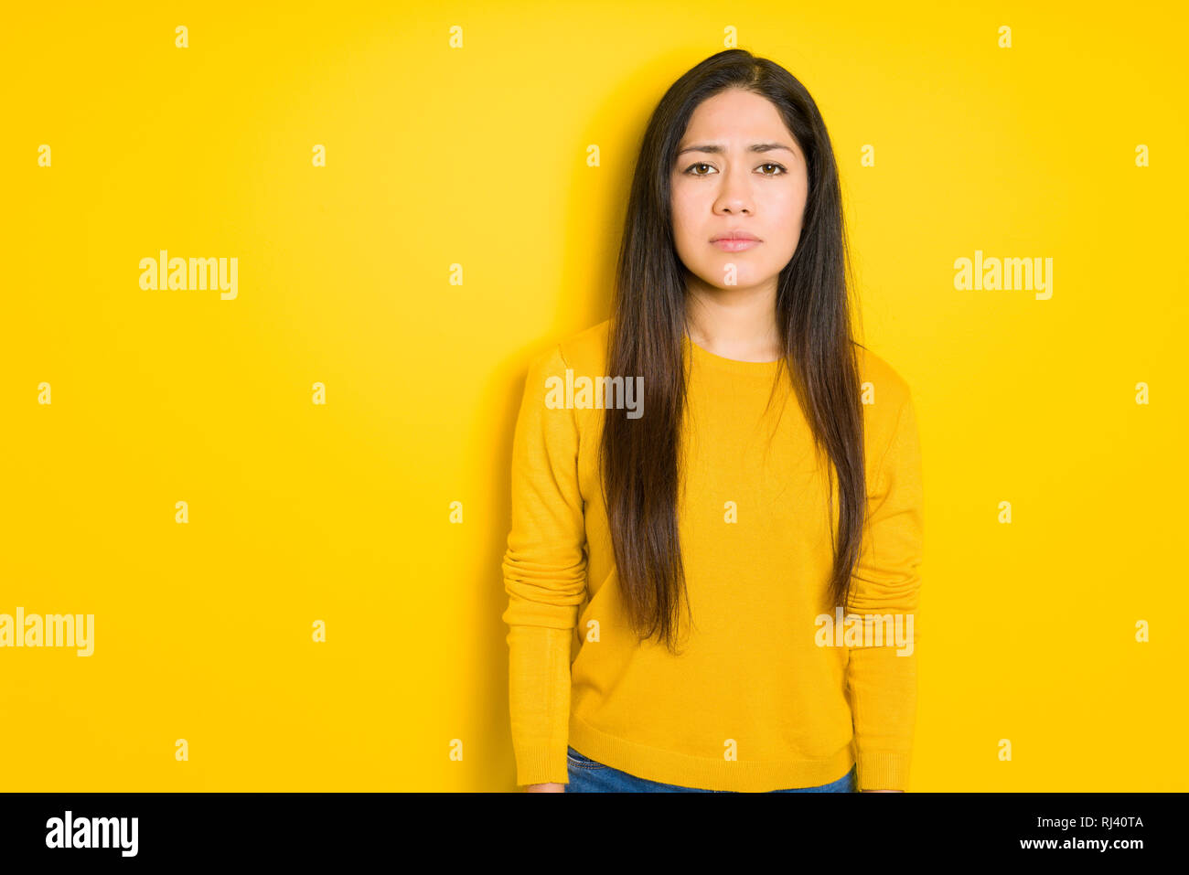 Beautiful brunette woman over yellow isolated background depressed and ...