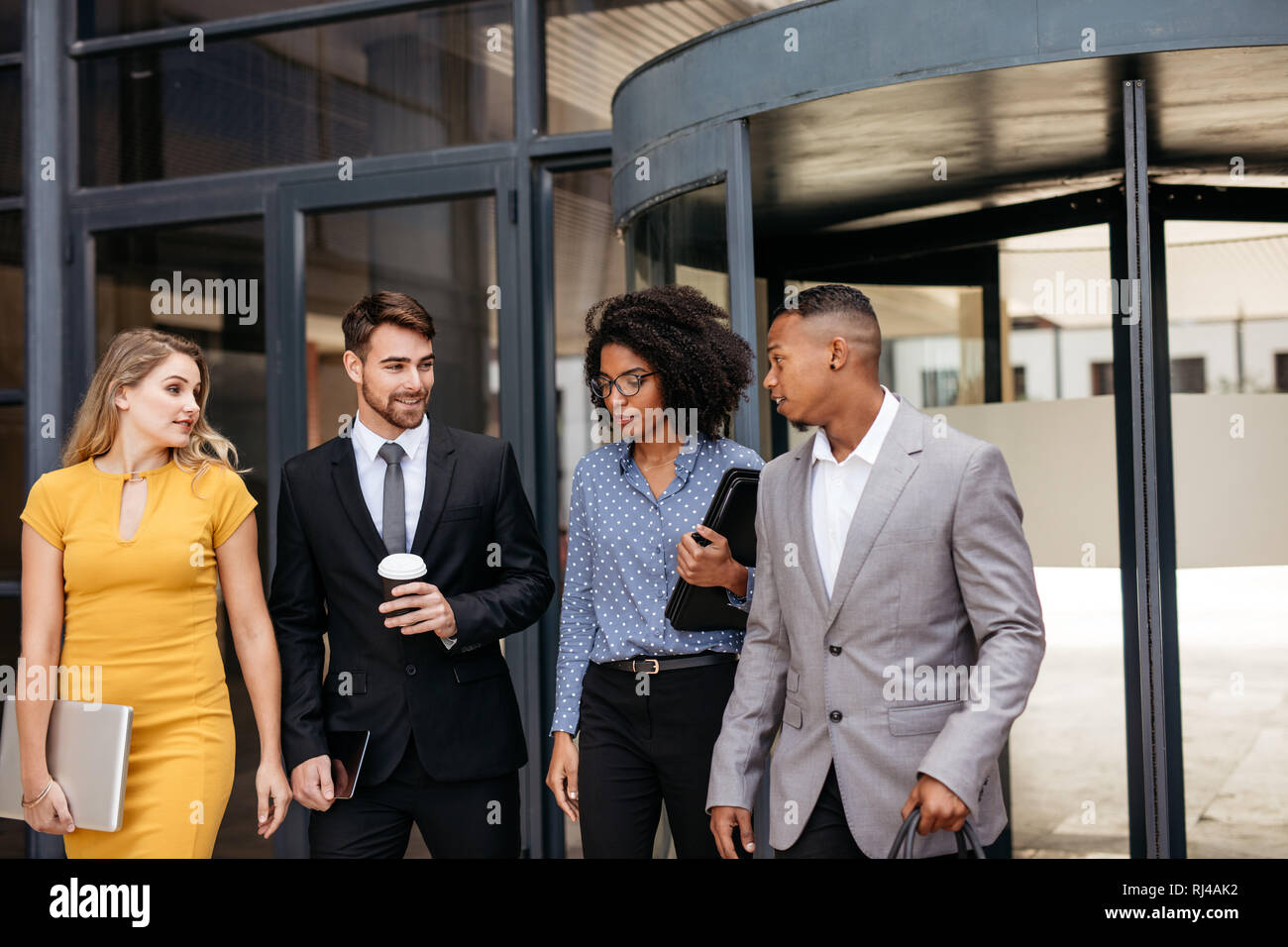 Group of corporate professionals walking out of office together and ...
