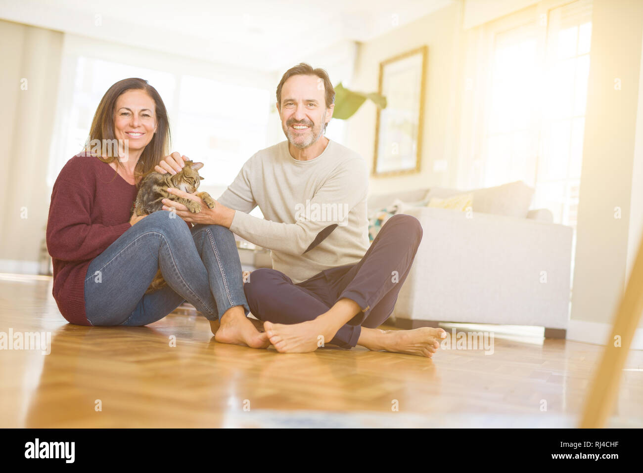 Beautiful romantic couple sitting together on the floor with the cat at ...