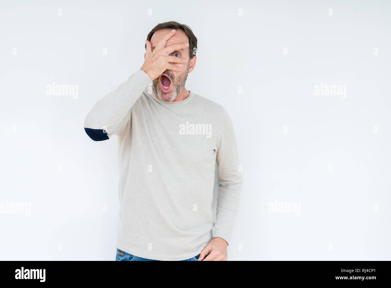 Elegant senior man over isolated background peeking in shock covering ...