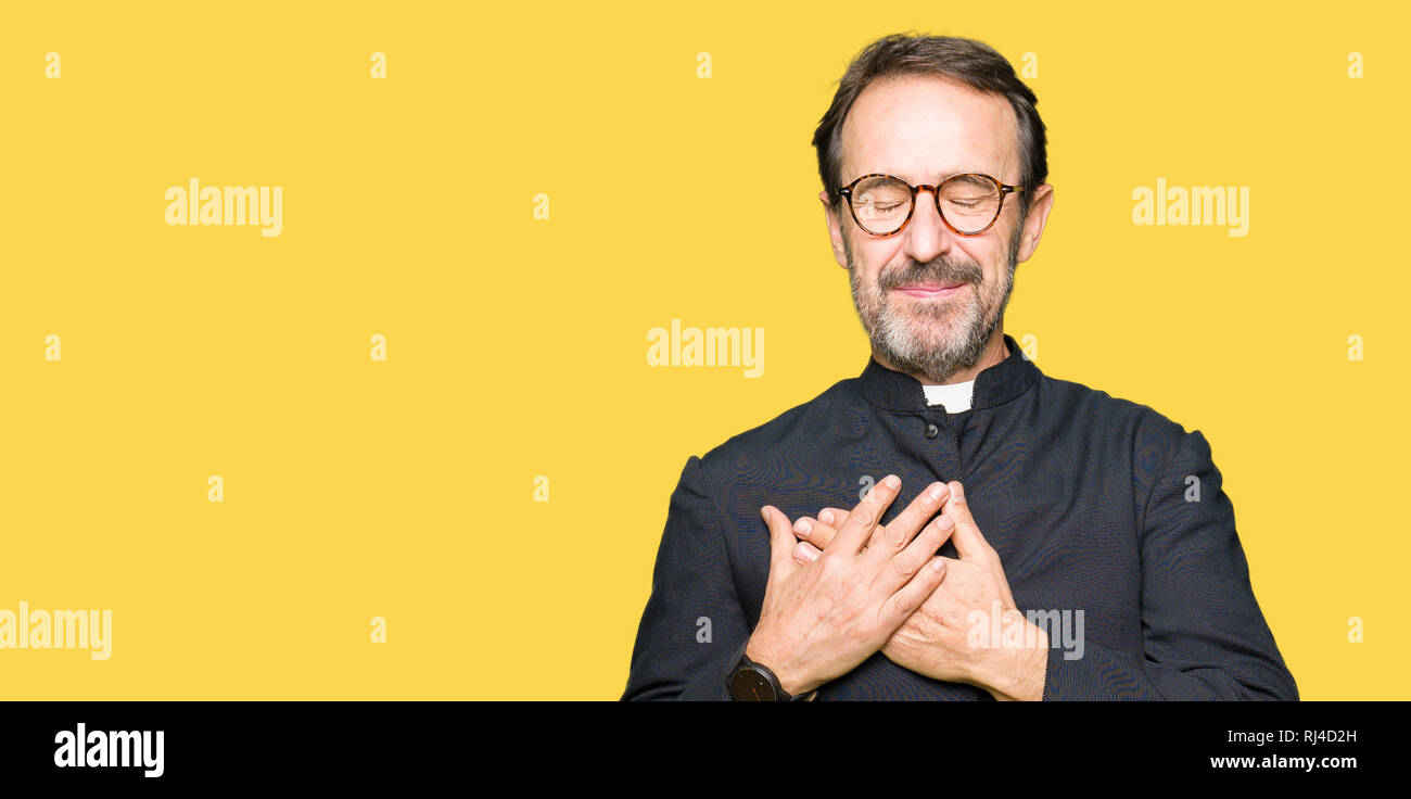 Middle age priest man wearing catholic robe smiling with hands on chest ...