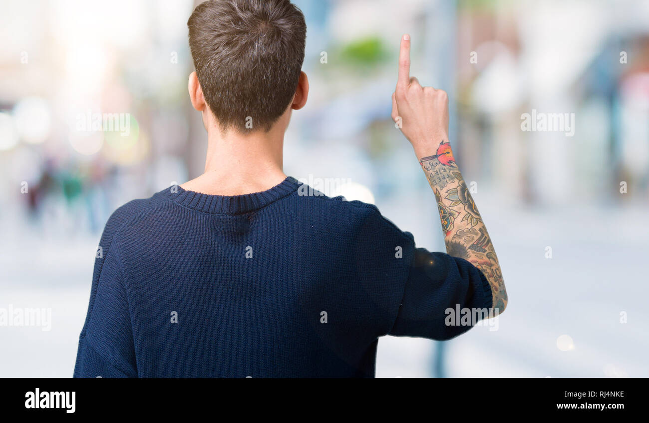 Young handsome man over isolated background Posing backwards pointing ...