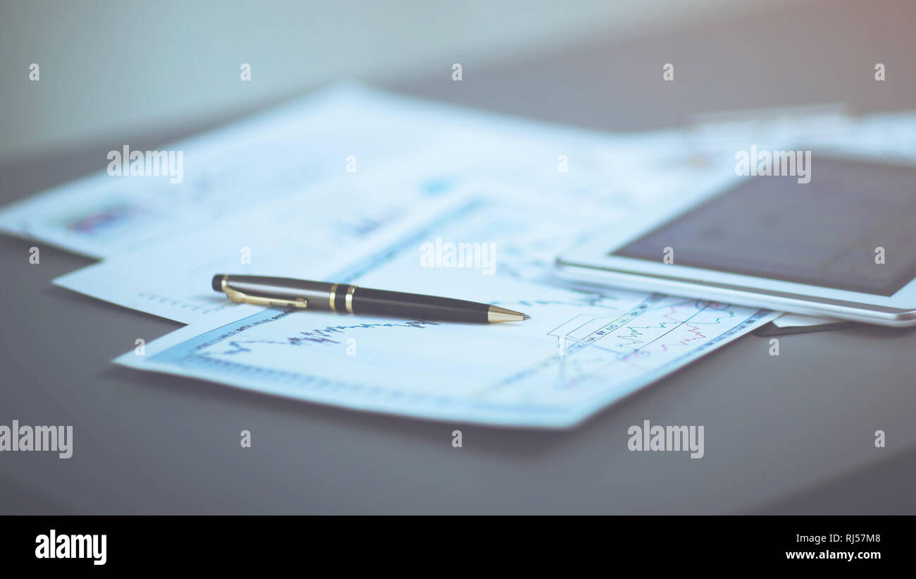 Tablet computer and financial charts, pen lying on the document Stock ...