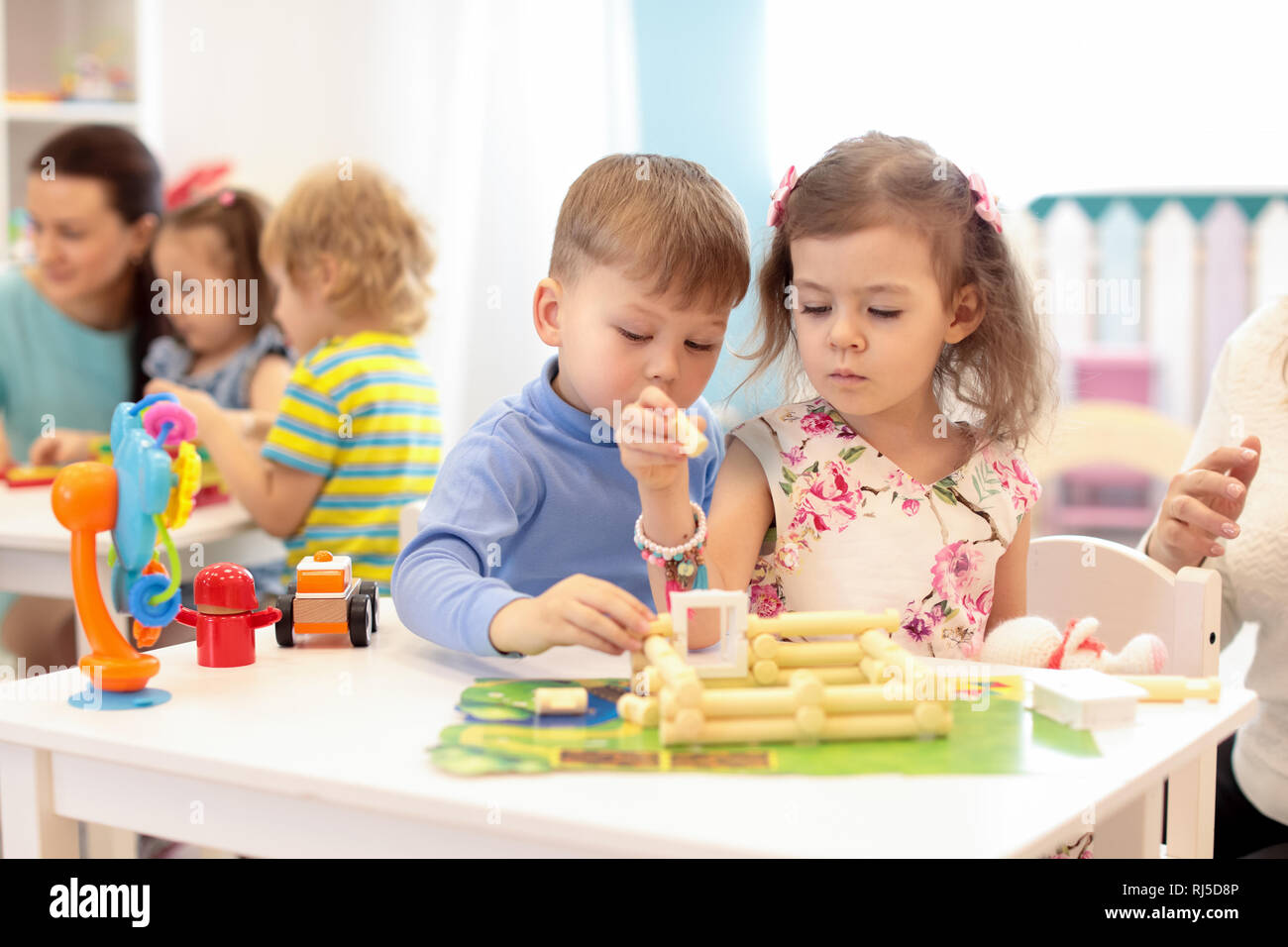 Group of kids play in kindergarten. Children building toy house with ...