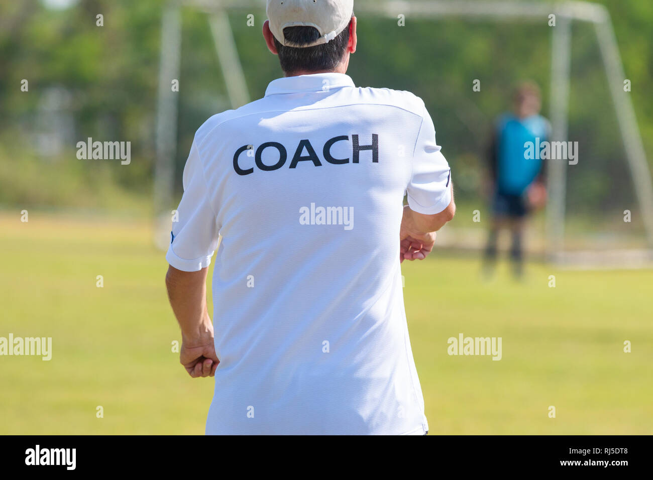 Back of football coach wearing white COACH shirt at an outdoor sport ...