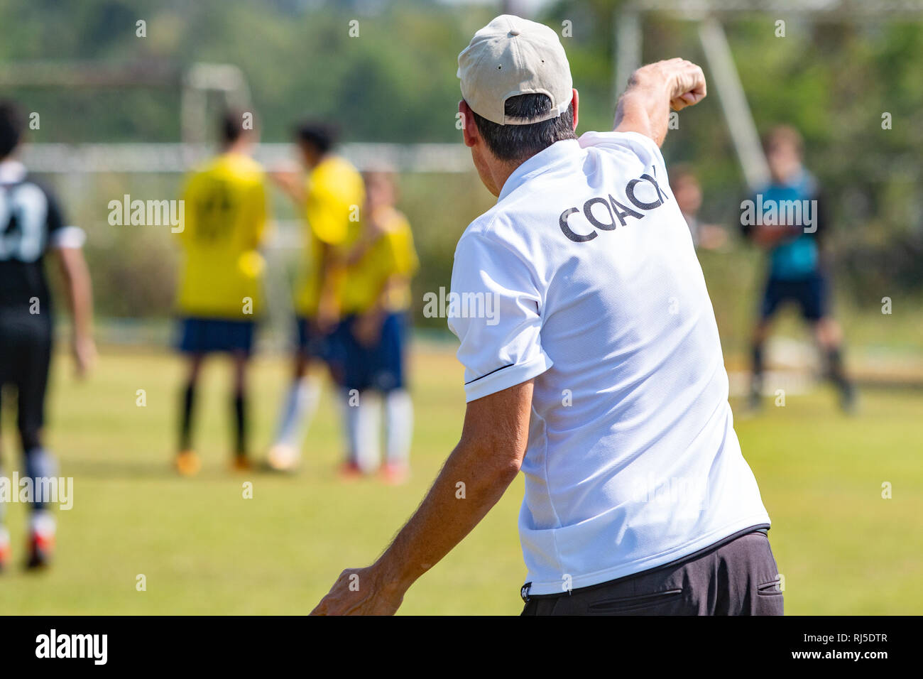Back of football coach wearing white COACH shirt at an outdoor sport ...