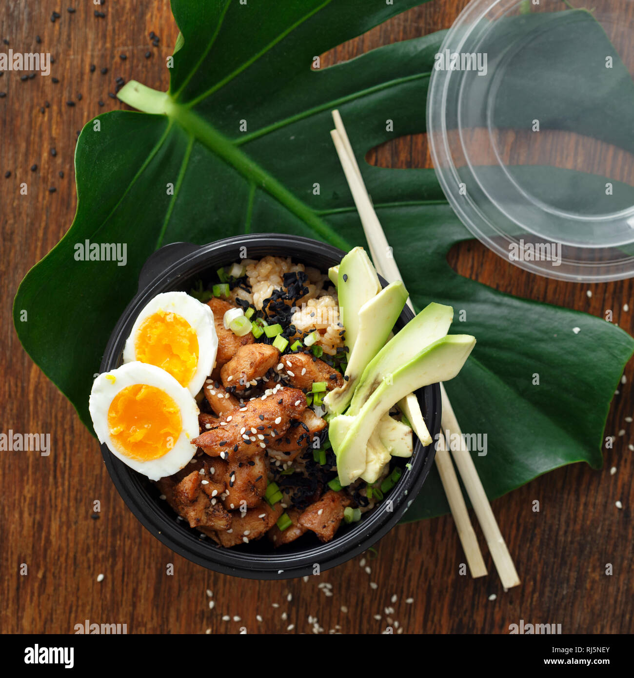 Two poke bowl of fried rice, chicken meat, avocado and eggs in box on ...
