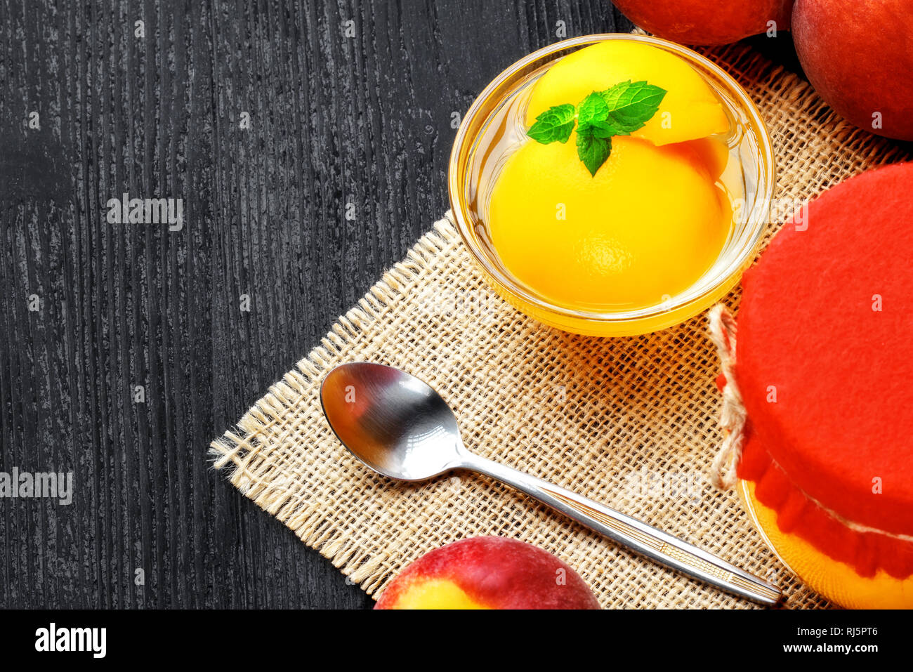 Peach compote with half peaches in glass jars on an old black wooden ...