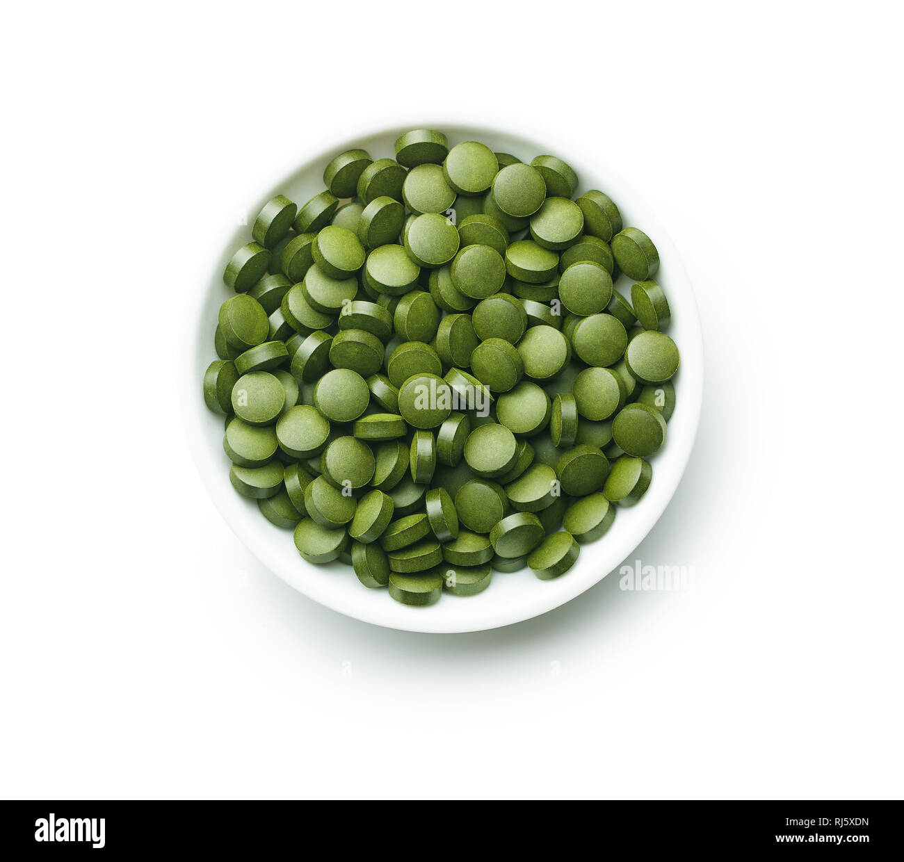 Green chlorella pills or green barley pills in bowl isolated on white ...