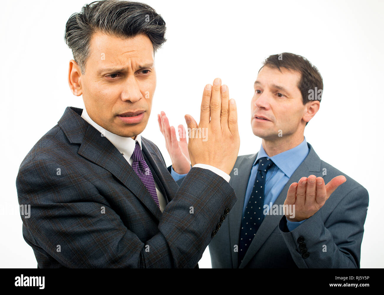 Two businessmen having an argument against a plain white background ...