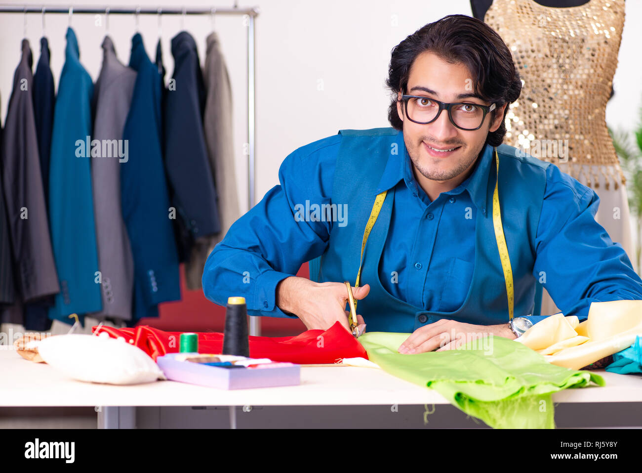 Young male tailor working at workshop Stock Photo - Alamy
