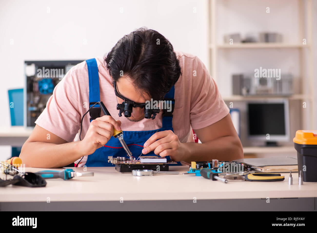 Young male contractor repairing computer Stock Photo - Alamy