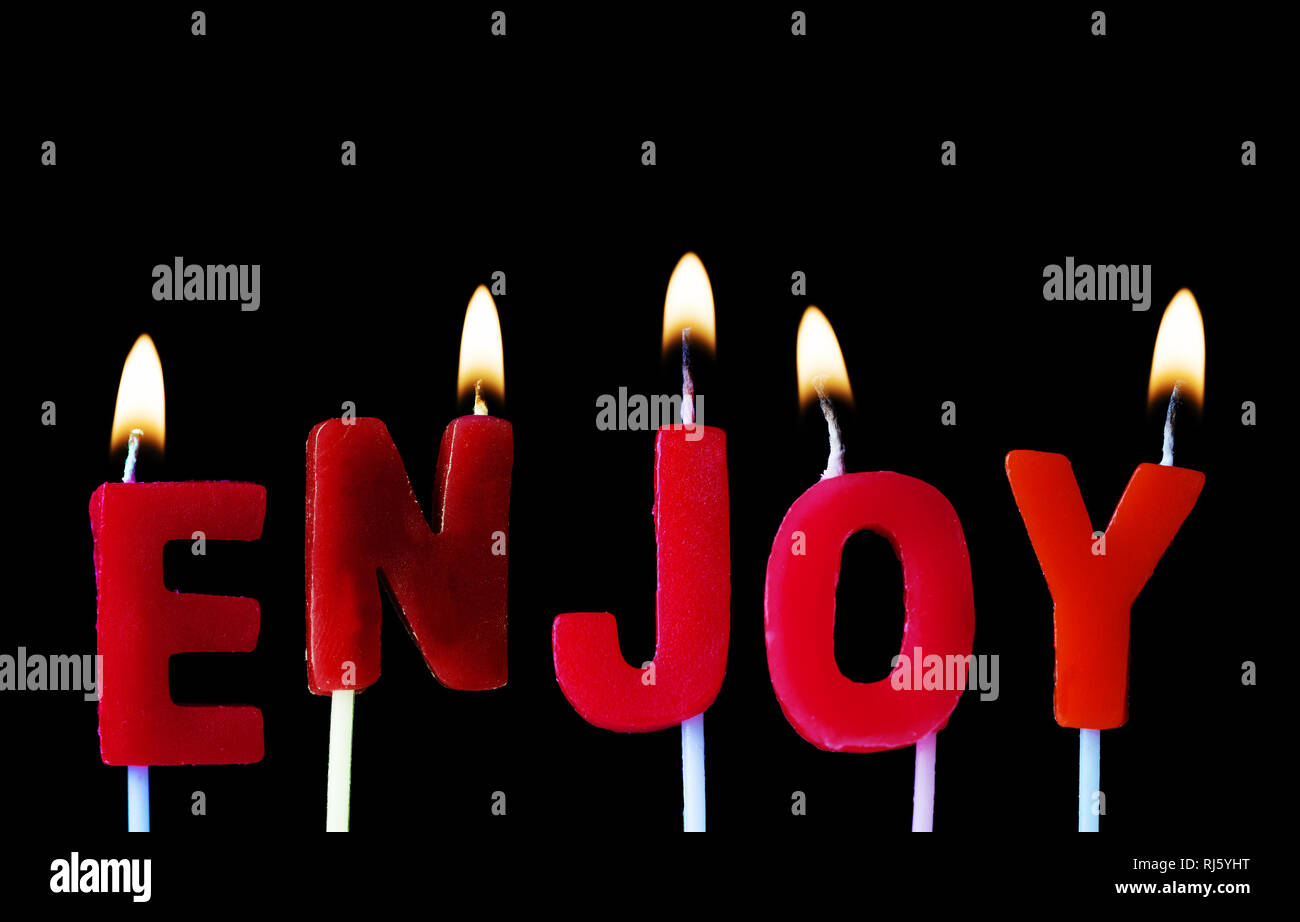 Enjoy spellt out in red birthday candles against a black background ...