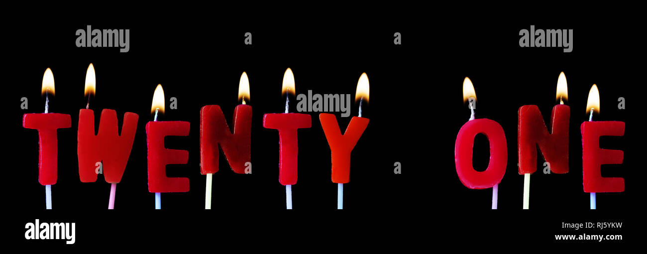 Twenty one spellt out in red birthday candles against a black ...