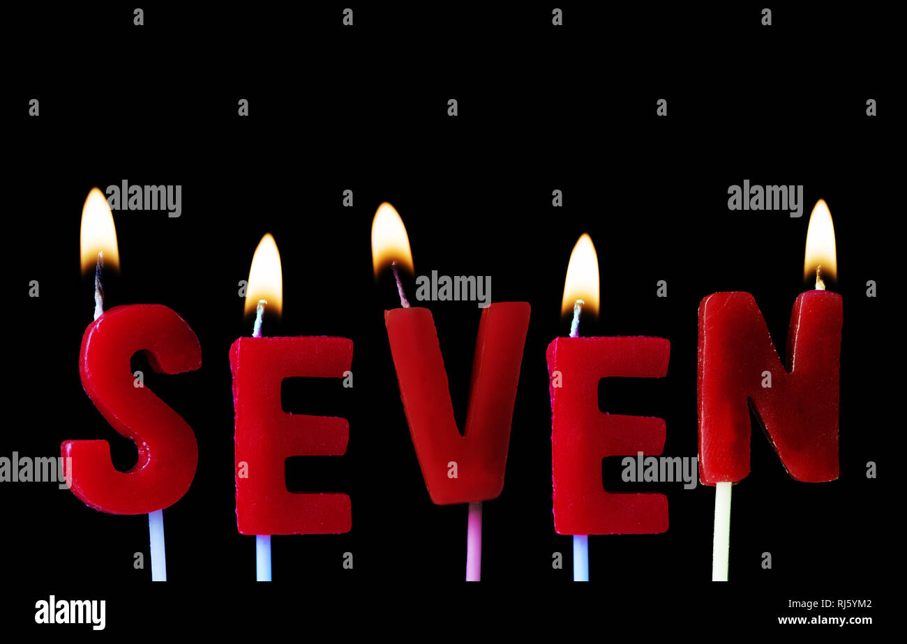 Seven spellt out in red birthday candles against a black background ...