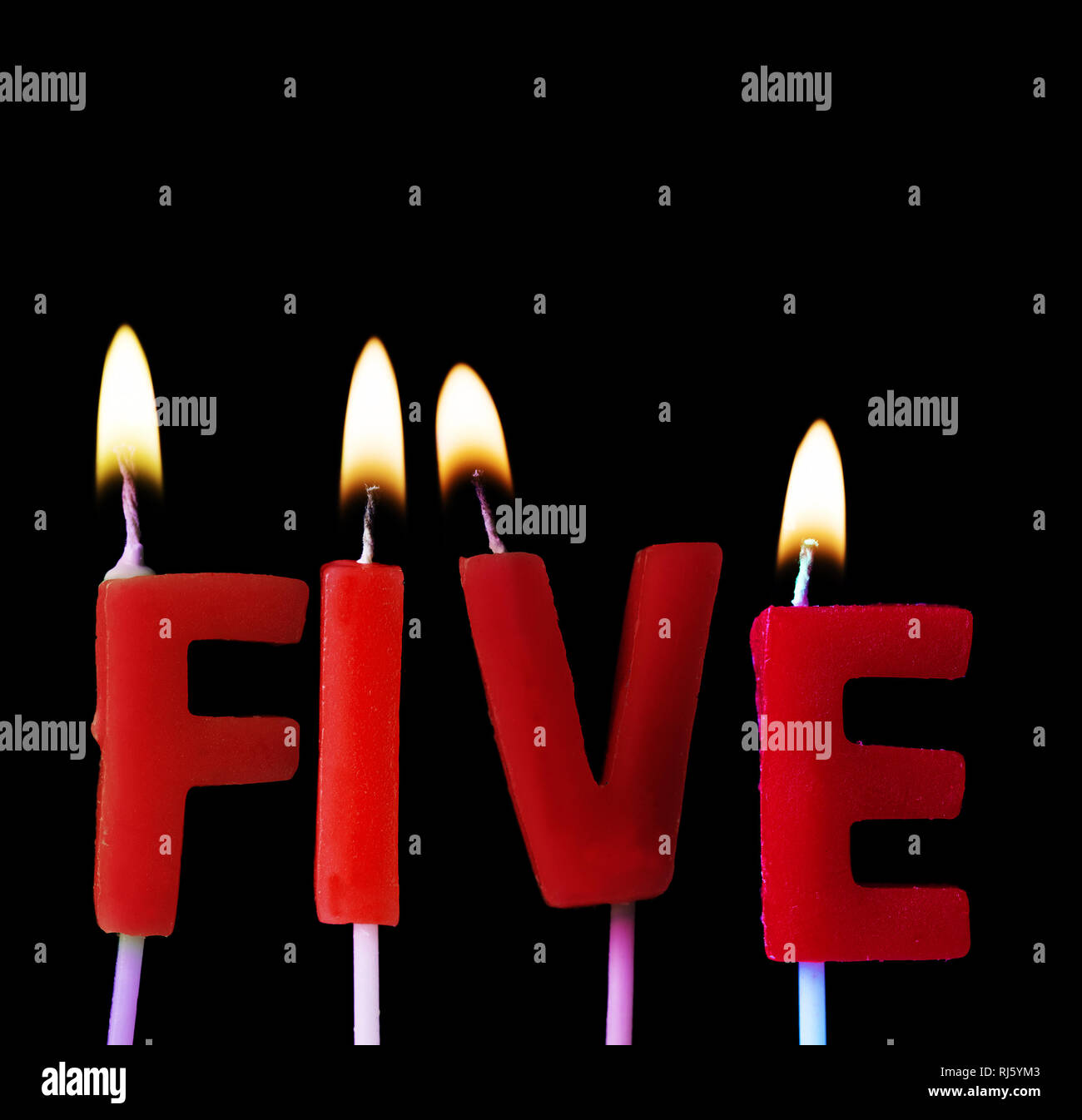 Five spellt out in red birthday candles against a black background ...