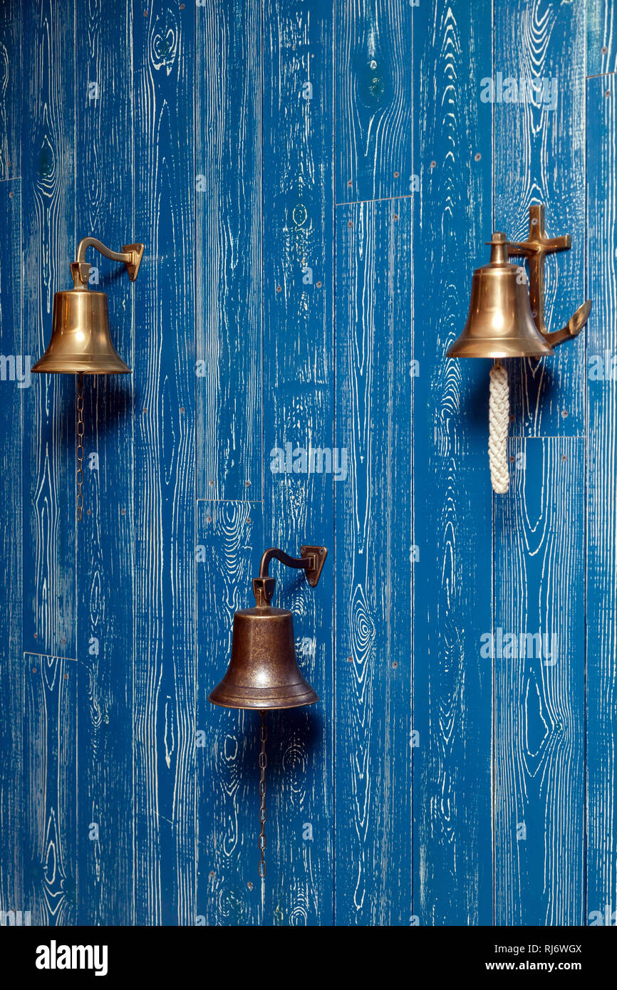 Three copper old vintage bells, doorbell, rope on a wooden blue aged ...
