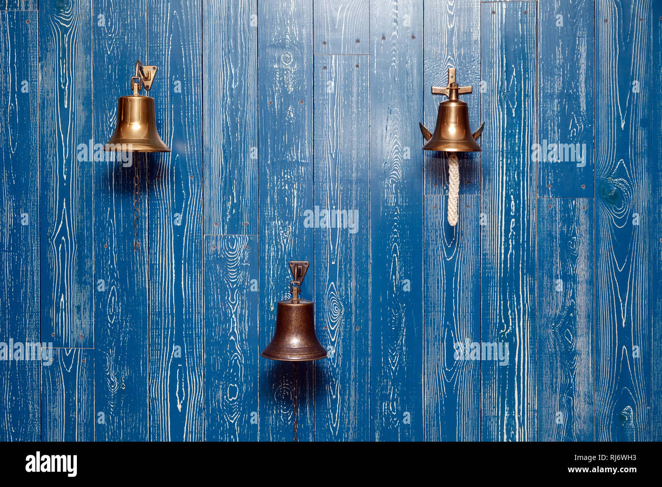 Three copper old vintage bells, doorbell, rope on a wooden blue aged ...