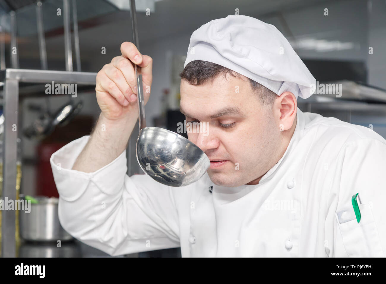 Closeup portrait man professional chef in white uniform is trying dish ...