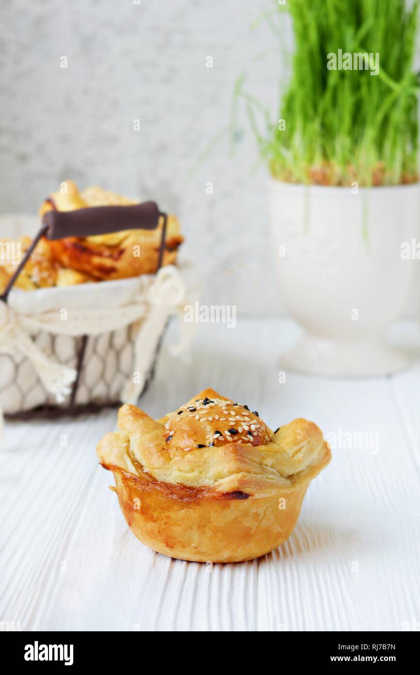 Meat pies from puff pastry with sesame seeds on a light background ...
