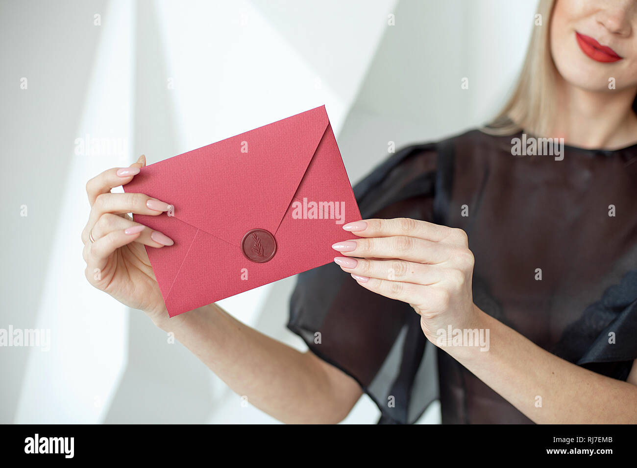 Close-up woman with slim body holding invitation envelope card in hands ...